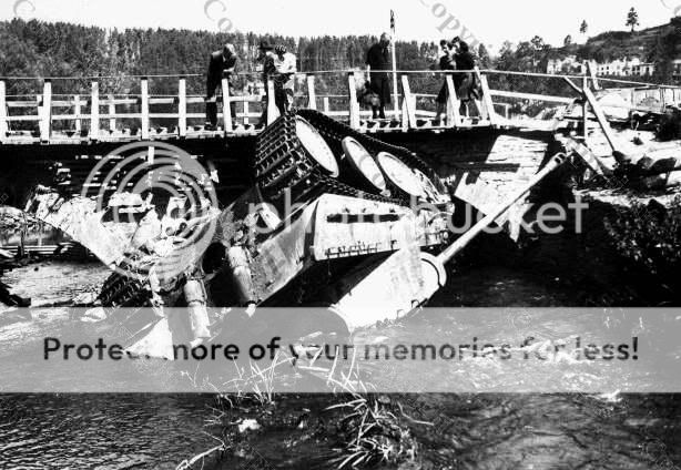 An Overturned German Panther tank lies in a shallow stream next to a ...